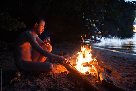 Naked Guy Sitting By The Fire On A Log On The Beach By Stocksy Contributor Demetr White