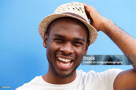 Close Up Cool Young Black Guy With Hat Smiling Against Blue Background