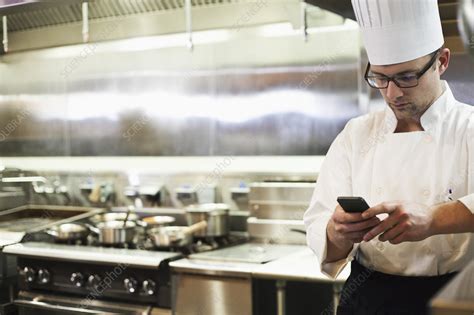 Male Chef Checking His Cell Phone In A Commercial Kitchen Stock Image