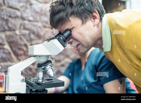 Man Student Or Scientist Examines Specimen Under Microscope Observing