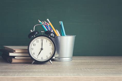 Alarm Clock On Wooden Table On Blackboard Background In Classroom Premium Photo