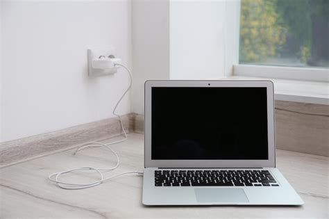 Premium Photo Modern Laptop With Charger On Floor Near White Wall