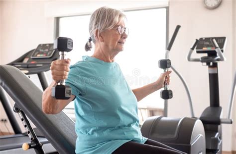 Athletic Old Senior Woman In Sportswear Exercising In Gym With Dumbells