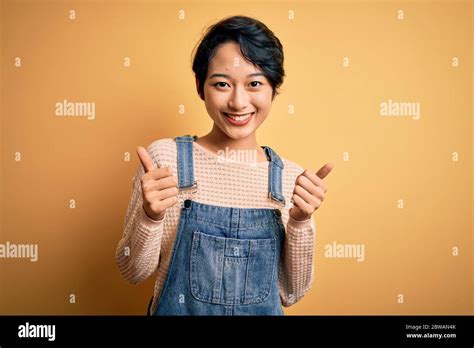 Young Beautiful Asian Girl Wearing Casual Denim Overalls Over Isolated