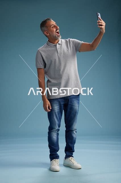 رجل عربي يلتقط صورة سيلفي بخلفية زرقاء صورة