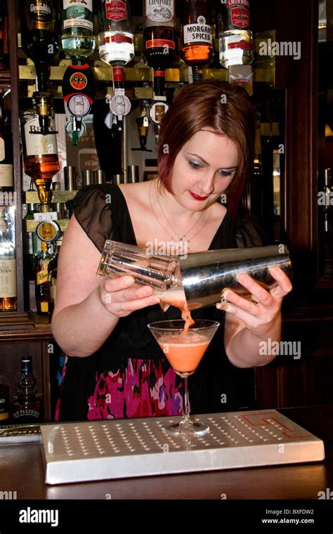 A Barmaid Pouring A Ready Made Cocktail Into A Glass Behind The Bar