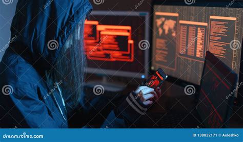 Girl Hacker In The Hood Holding The Phone In Hands Trying To Hack The Mobile Device Cloud In The