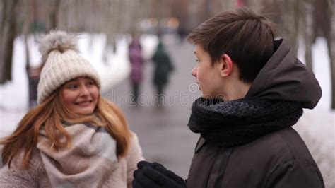 Thoughtful Teen Boy Standing On Park Alley As Joyful Girl Covering Eyes