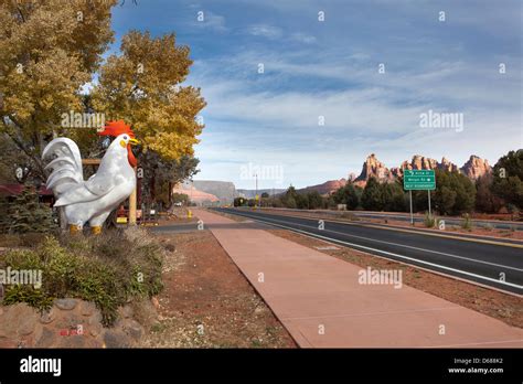 A Rooster Figure Next To A Road And The Red Rocks In The Backdrop