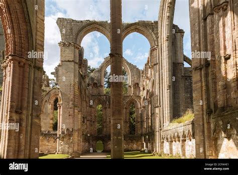 Historical Stone Building With Arched Passages And Green Grass On