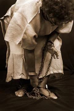 Black Woman Tied To Old And Rusty Chains And With An Iron Mask On Her