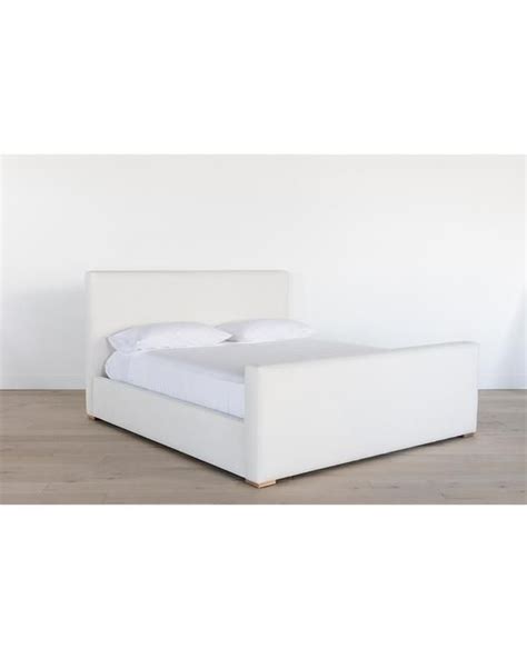 A White Bed Sitting On Top Of A Hard Wood Floor Next To A White Wall