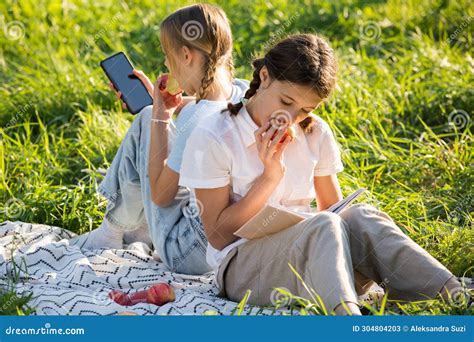 Two Teenage Girls Spend Time On Green Grass Lawn In Park Together