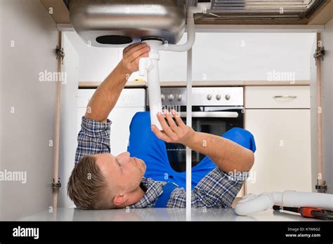 Male Plumber Lying On Floor While Fixing Pipe Into The Steel Sink Stock Photo Alamy