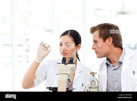 Scientists Looking At A Slide Under A Microscope Stock Photo Alamy