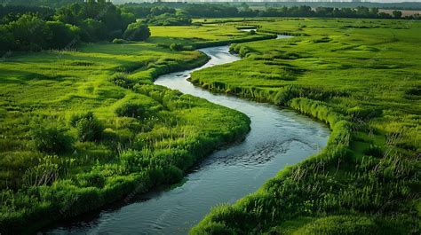 A Lush Green Landscape With A River Running Through It The River Is Winding Its Way Through The