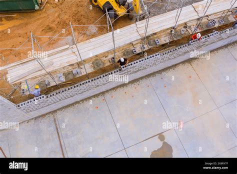 On Construction Site Mason Makes Concrete Wall Using Cement Blocks While Standing On