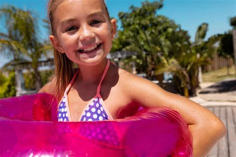 Portrait Happy Biracial Girl Smiling Applying Sunscreen Swimming Pool
