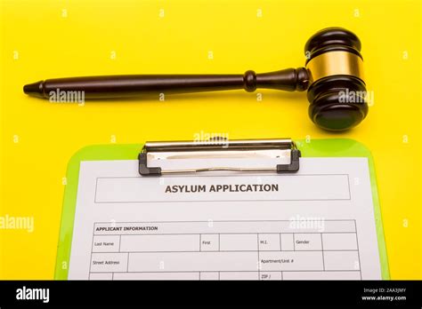 Asylum Concept Showing An Application Form For Asylum On A Yellow Background With A Gavel Stock