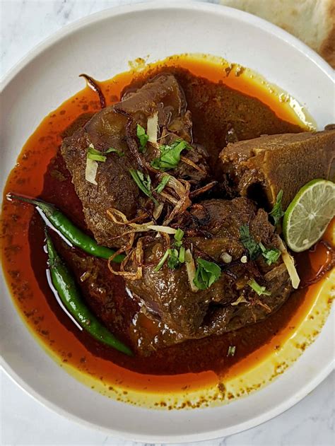 Download Delicious Nihari Served With Garnishing On A Wooden Table Wallpaper