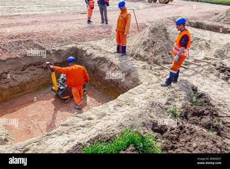 Worker Is Compacting Gravel With Vibration Plate Compactor Machine In Square Trench Stock Photo