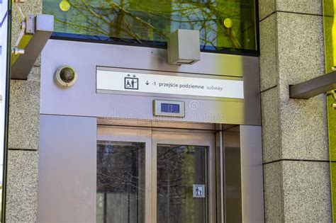 Modern Glass Elevator Entrance To Underground Pedestrian Subway With Sign And Surveillance