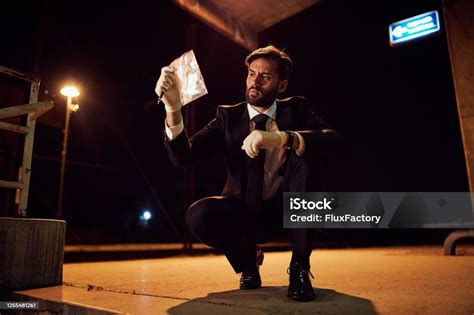 Police Detective Examining Collected Evidence On A Crime Scene Stock