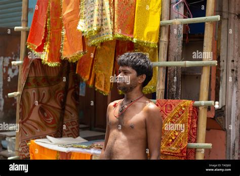 A Half Naked Man Stands In Front Of Orange Cloth Selling Booth In The Sweltering Heat In The