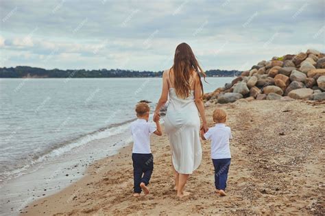 Premium Photo Young Mother Walks With Her Sons On The Beach