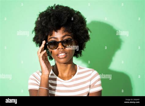 Woman Adjusting Sunglasses While Standing Against Green Background