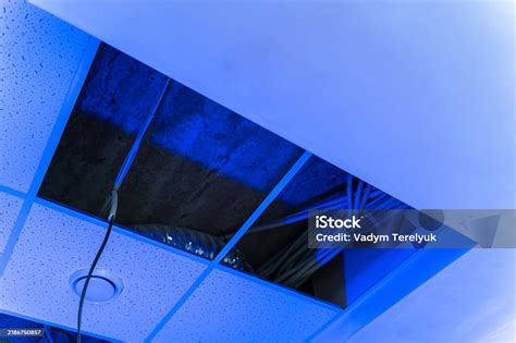 Exposed Ceiling Tiles Revealing Electrical Wiring In A Modern Interior