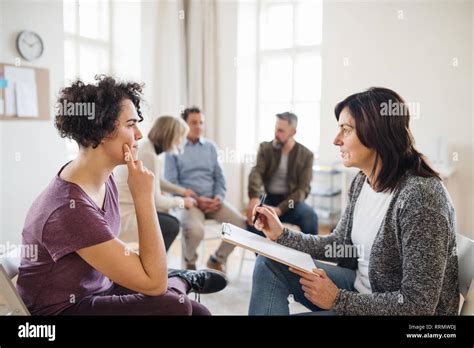 A Senior Counselor With Clipboard Talking To A Young Woman During Group