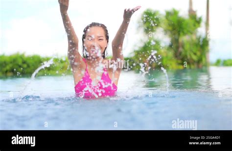 A Happy Smiling Young Woman Chest High In A Resort Swimming Pool Smiles