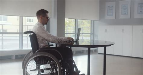 Positive Disabled Young Woman In Wheelchair Working In Office Stock
