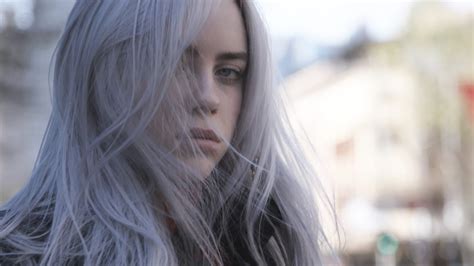 Billie Eilish Is Facing One Side Having White Color Hair Standing In Blur Background Hd