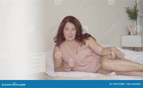Pretty Mature Woman Drinking Tea Or Coffee Lying In Bed In The Morning