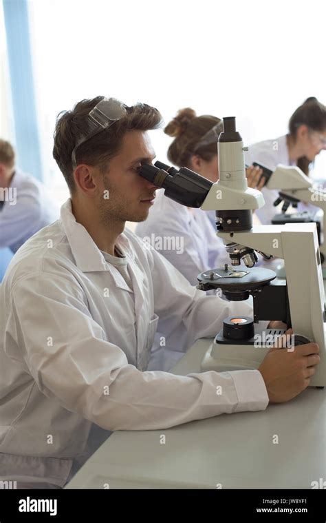 College Students Using Microscope While Practicing Experiment In Lab Stock Photo Alamy