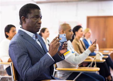 african american man recording lecture on smartphone at conference hall