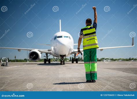 Airport Worker Raising Hand And Directing Passenger Plane In Right