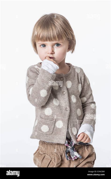 Portrait Of Cute Girl With Finger In Mouth Against White Background