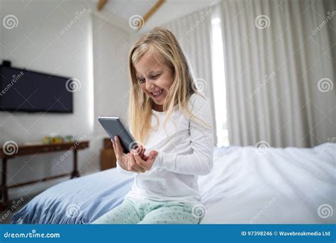 Menina Que Usa O Telefone Celular Na Cama No Quarto Foto De Stock
