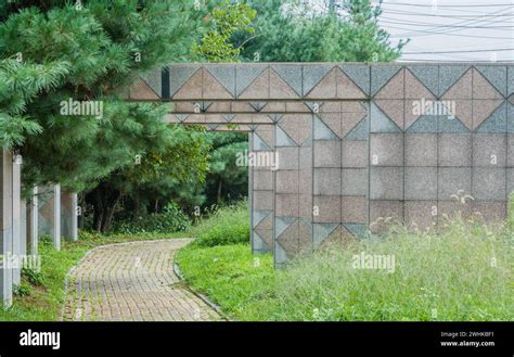 Brick Walkway Through Series Of Walls With Triangular Patterns In