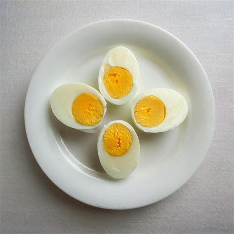Two Boiled Eggs Halved On A Plate In Top View On A White Background