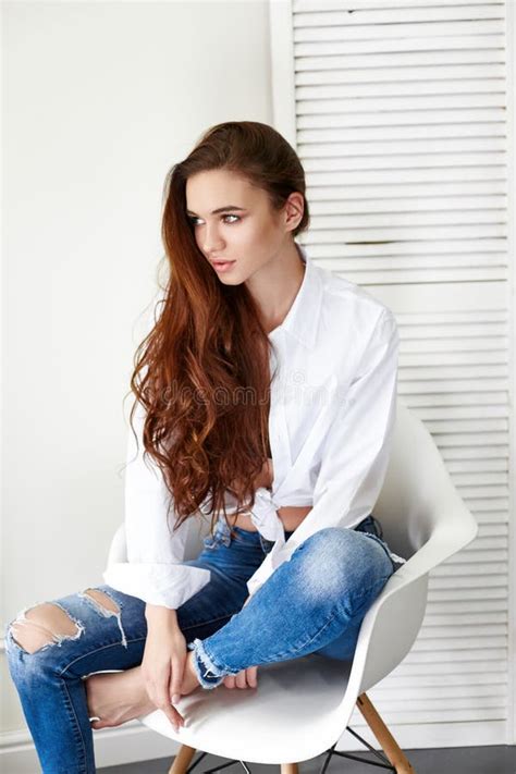 Bella Ragazza Sexy In Camicia Bianca Dei Jeans Che Si Siede Su Una