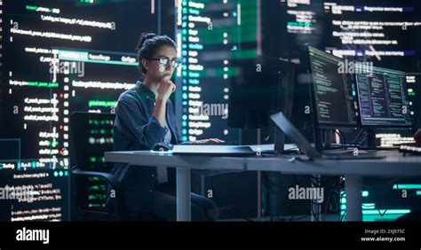 Focused Woman Working On A Computer Typing Lines Of Code That Appear On Big Screens Surrounding