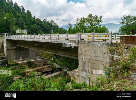 A Concrete Solid Slab Bridge Connecting Two Small Hills At The Base In