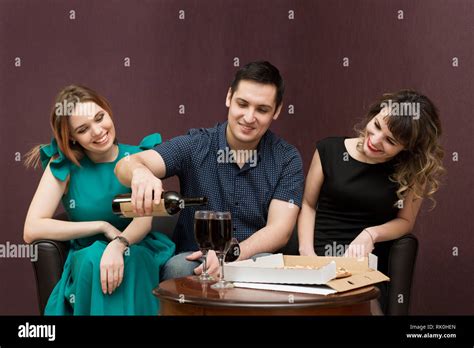 Girls Seduce A Man Having Fun And Drinking Wine Eating Pizza Stock