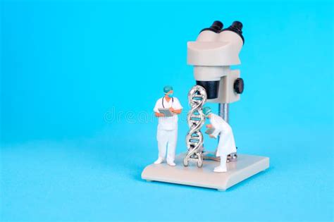 Miniature Scientists Examining Dna Structure Under Microscope In