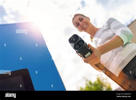 Happy Woman Holding A Dc Ccs Ev Charging Connector On A Kw Hypercharger Or Supercharger For