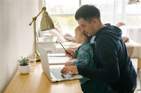 아버지는 작은 아기를 안고 집에서 노트북으로 일합니다 원격 작업의 개념 12 17 개월에 대한 스톡 사진 및 기타 이미지